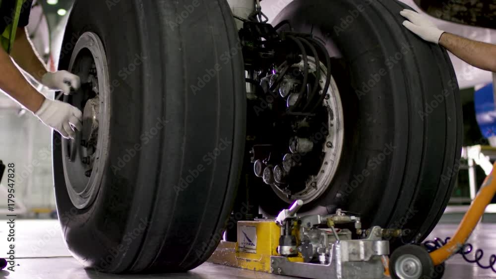 Airport worker checking chassis. Engine and chassis of the passenger airplane under heavy ...