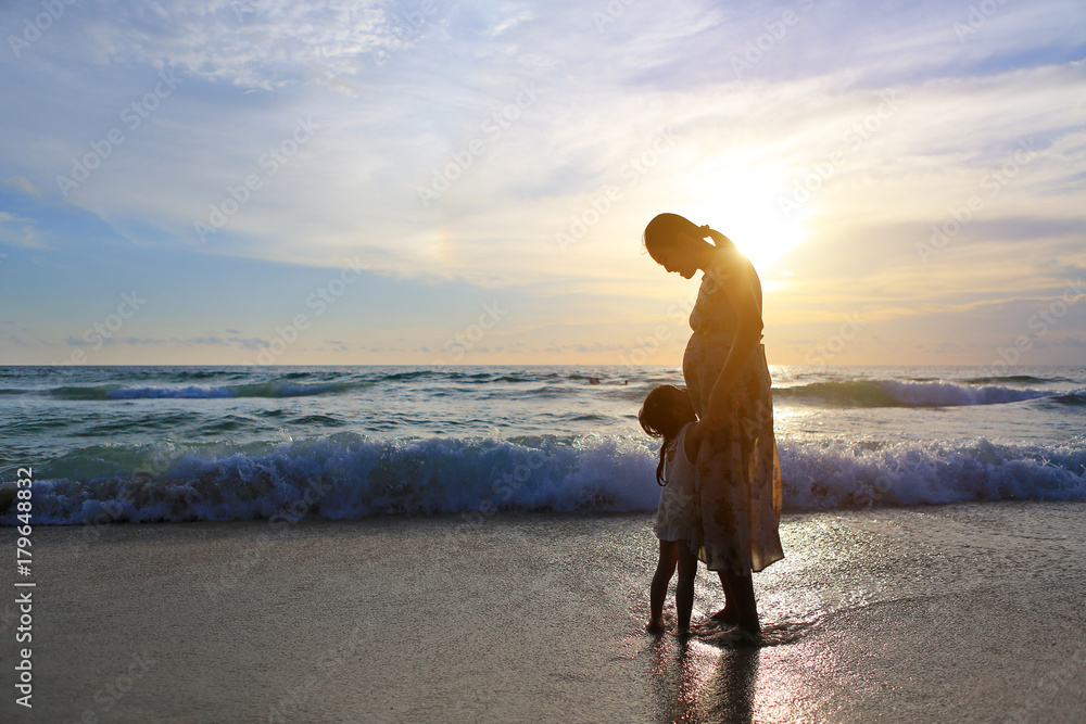 Silhouette happy pregnant mother and daughter relaxing on the beach at ...