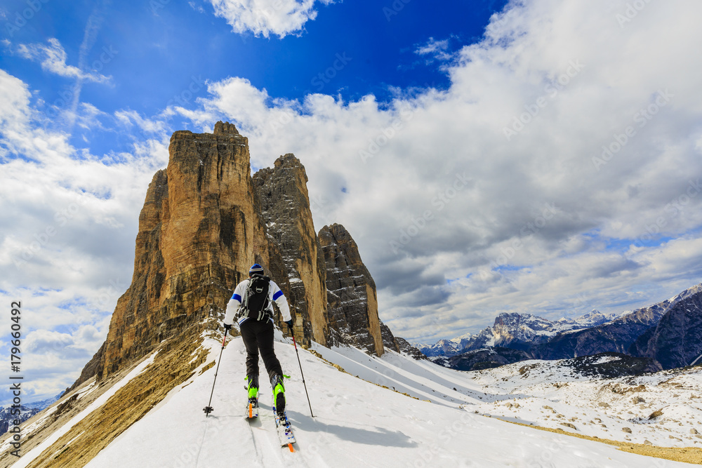 Mountaineer backcountry ski walking up along a snowy ridge with skis in ...