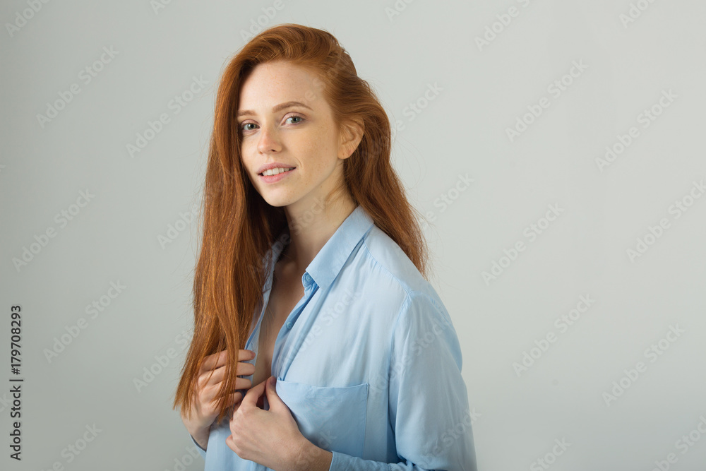 beautiful young girl with red hair unbuttoned her shirt on a light ...