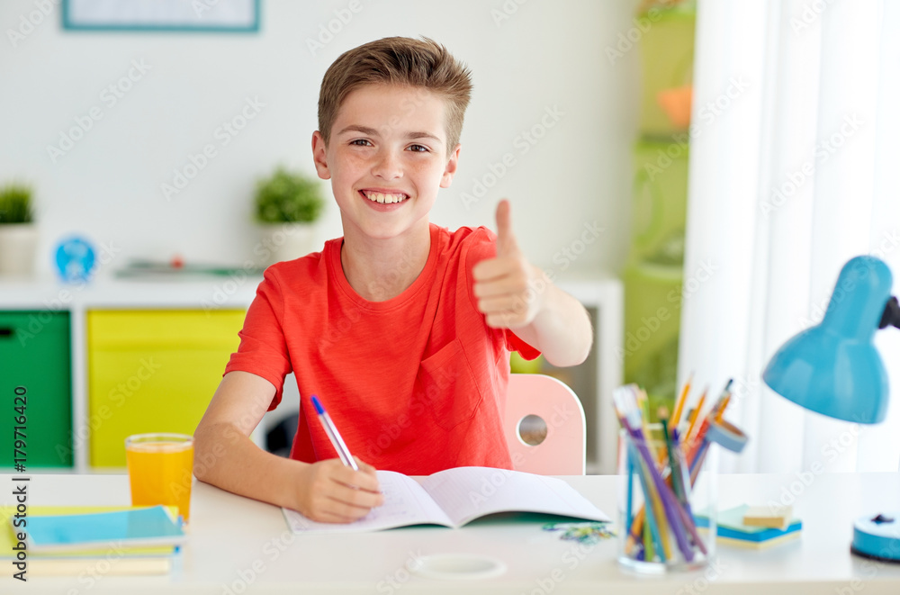 happy student boy writing to notebook at home Stock Photo | Adobe Stock