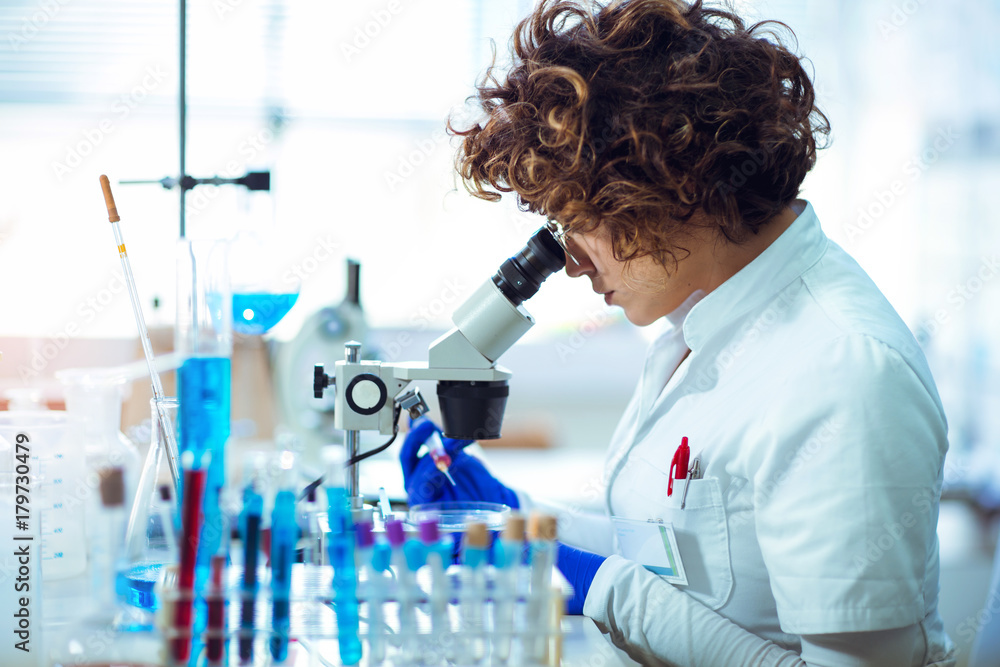 Woman scienist in laboratory. Young scientist looking through a ...