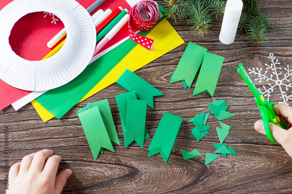 Child carves details Christmas wreath with a candle. Made by own hands ...