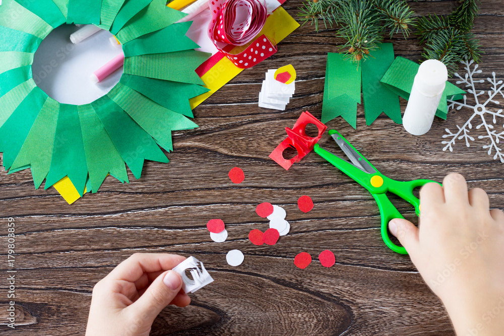 Child carves details Christmas wreath with a candle. Made by own hands ...