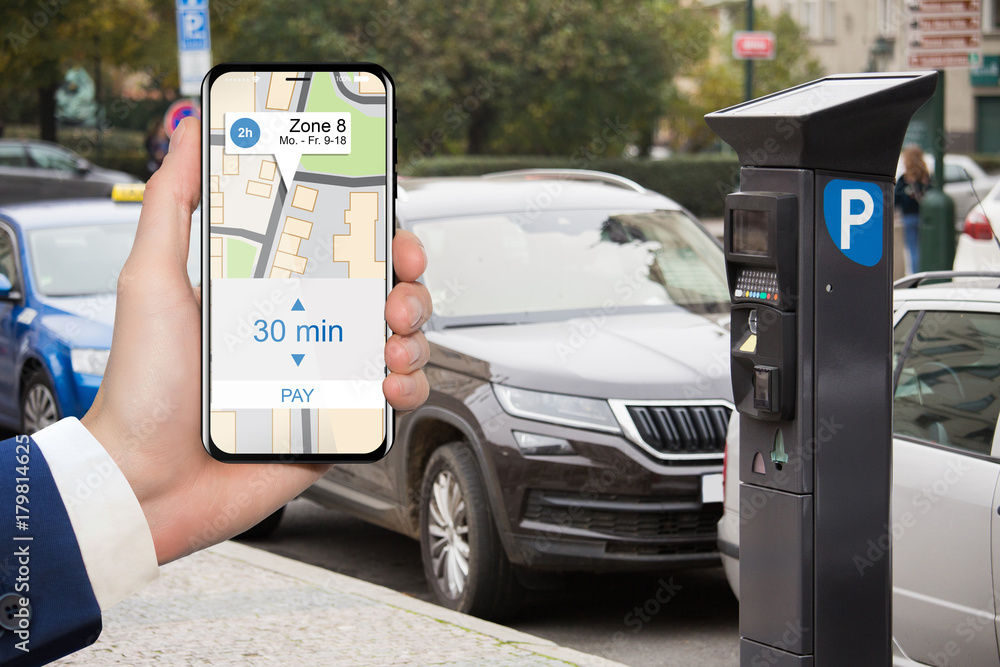 Hand with phone on the background of the parking machine. On the screen ...