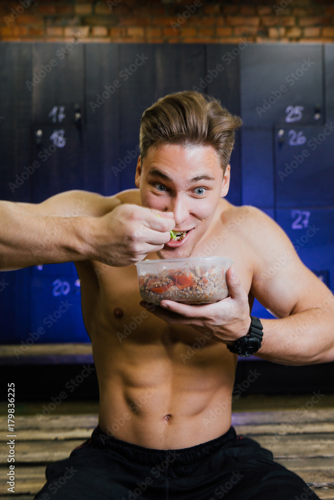 Fitness model of a bodybuilder guy eating food from a plastic container ...