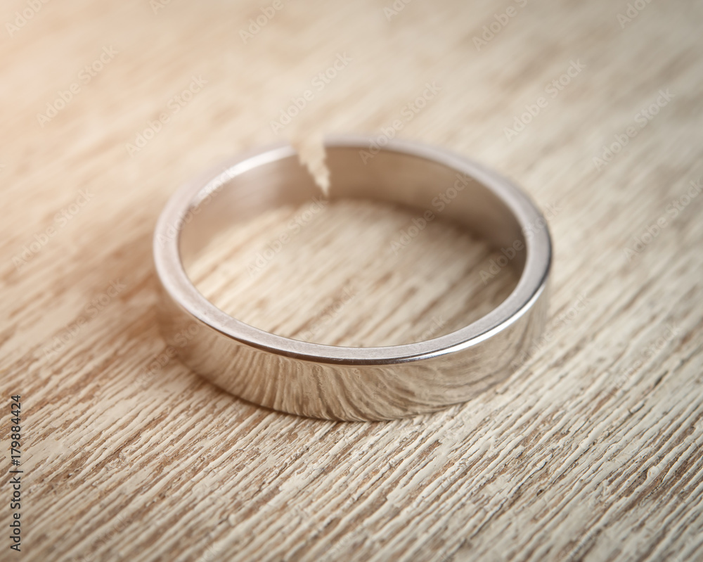 Cracked silver wedding ring on wood,Divorce and ending relationship ...