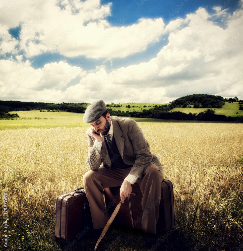 Emigrant in the countryside sitting on cardboard suitcases foto de ...