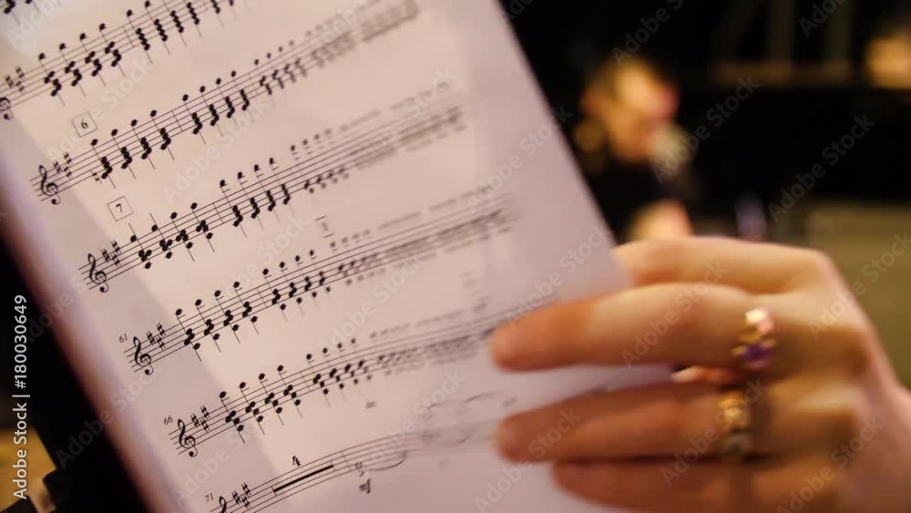 Beautiful female music composer looking at music notes. Woman looks at ...