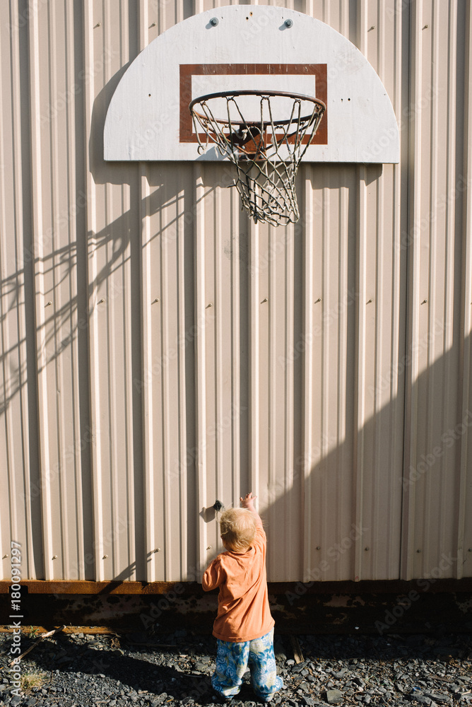 Boy playing under basketball hoop Stock Photo | Adobe Stock