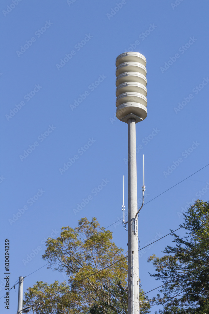 Siren tower over tree tops against a clear blue sky, space for text ...