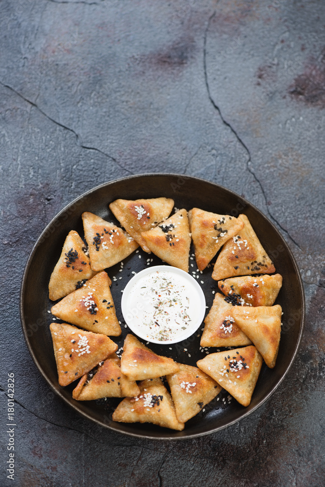 Metal plate with meat samosas on a cracked asphalt background, elevated ...