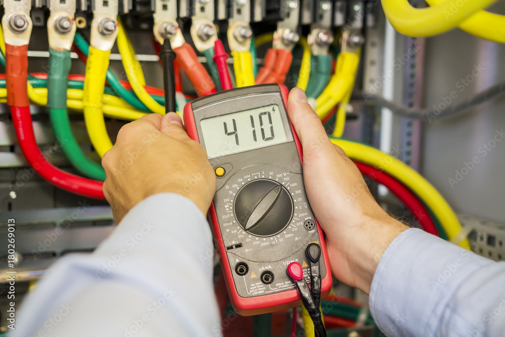 Multimeter in hands of electrician in power high voltage three phase ...