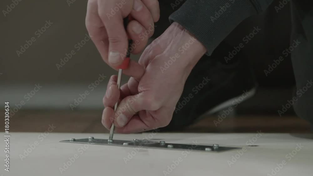 Close up of male hand holding small screw or bolt and putting it into ...