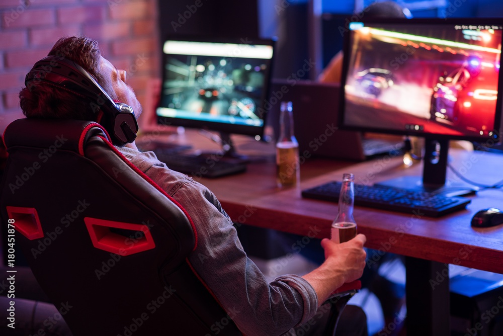 Feeling tired. Back view of relaxed young gamer in headphones is ...