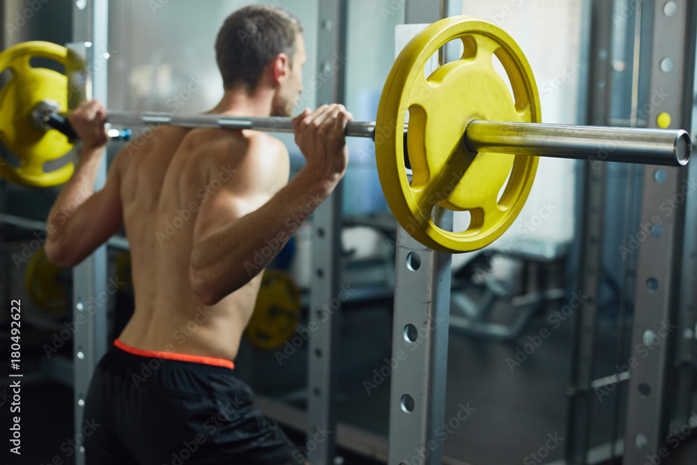 Rear view portrait of handsome muscular man with bare back lifting ...