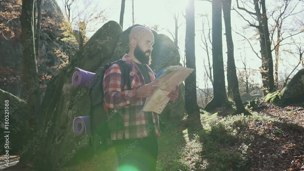 Stylish hipster man traveler with backpack holding map and exploring on ...