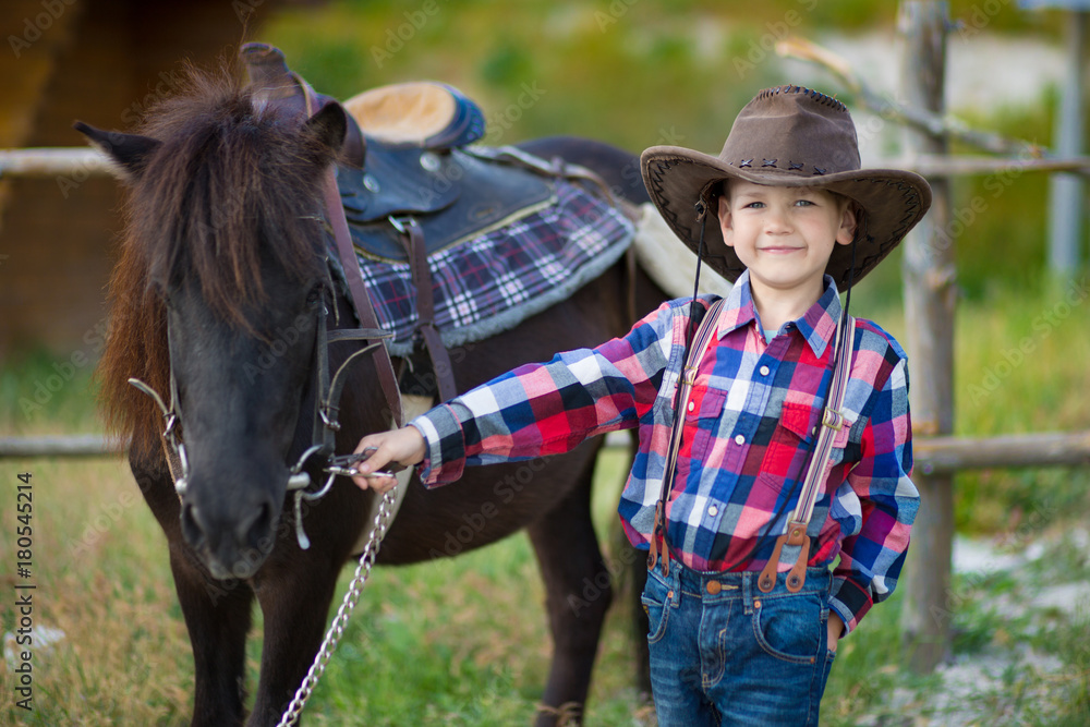 Cute fermer handsome boy cowboy in jeans enjoying summer day in village ...