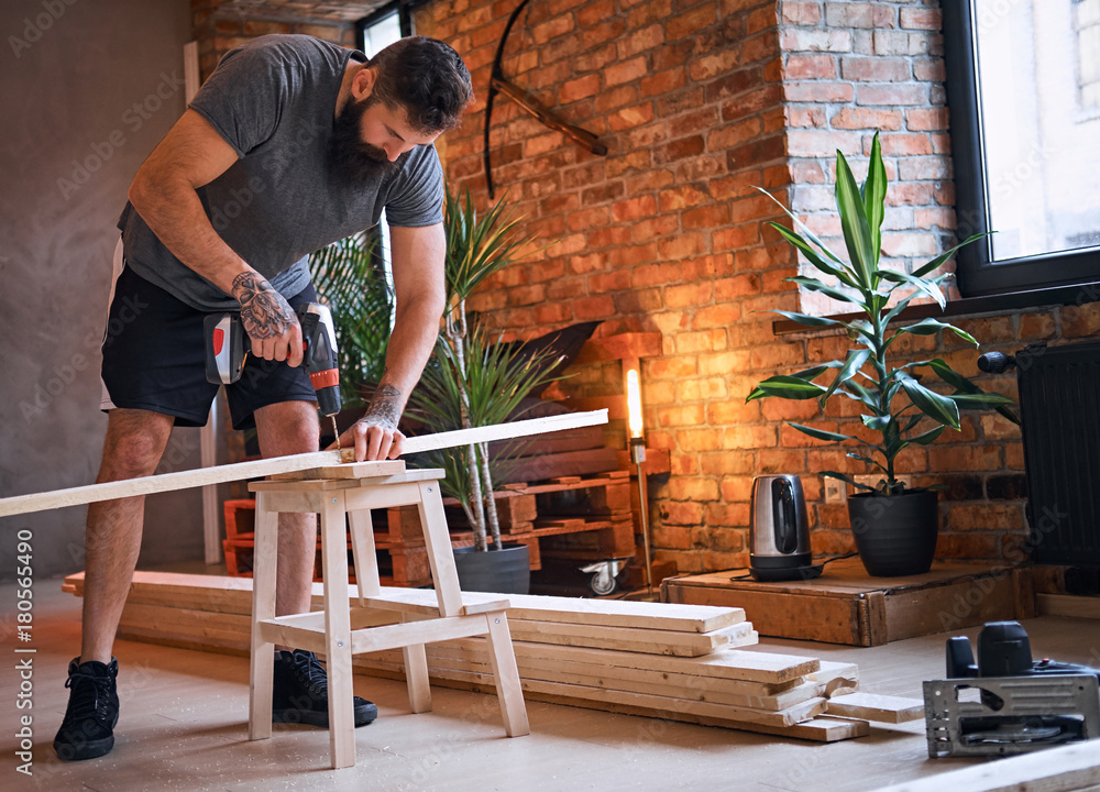 Carpenter drilling a hole in a board in a room with loft interio Stock ...