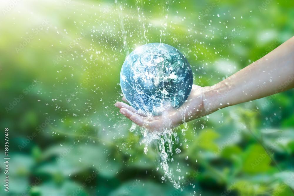 Water pouring on planet earth placed on human hand for saving resources ...