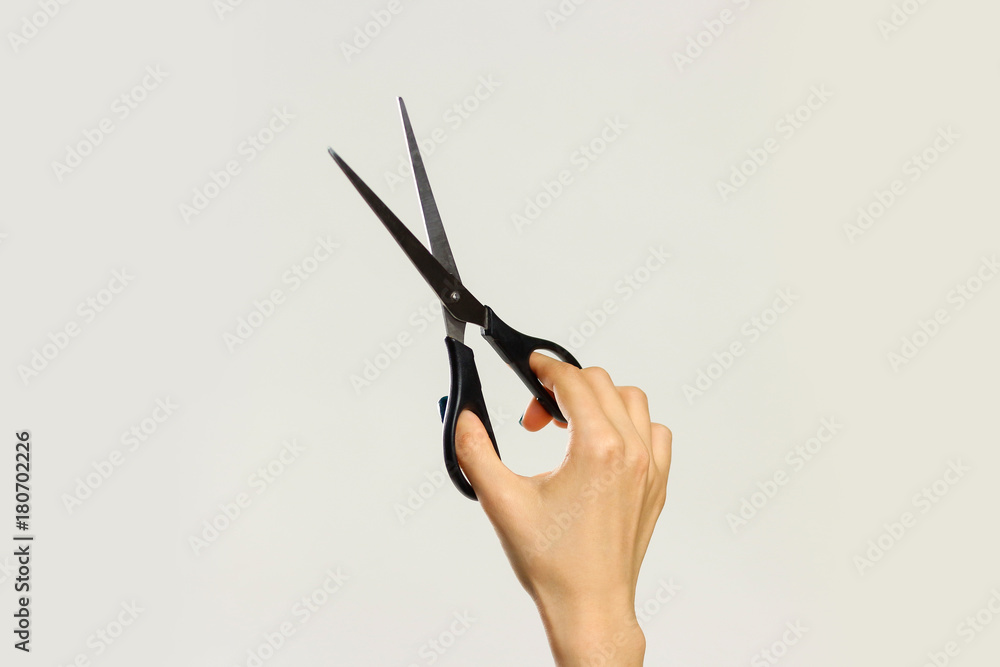 Female hands holding black scissors. Isolated on gray background ...