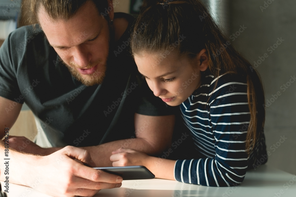 Father and daughter looking at mobile phone Stock Photo | Adobe Stock