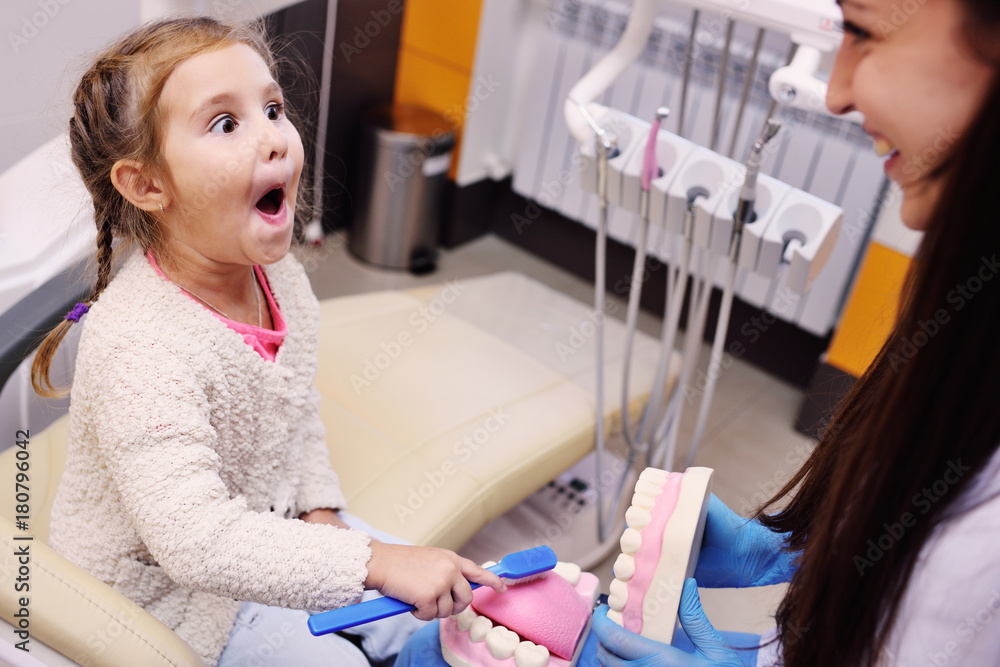 the dentist shows the little girl how to clean the teeth with a ...
