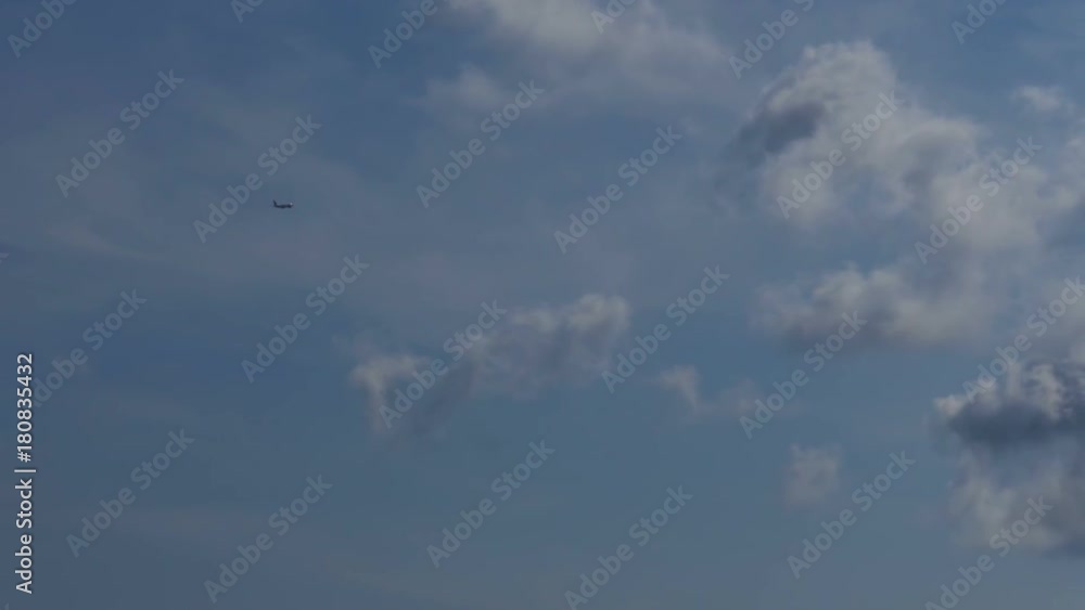 The passenger airplane is flying far in the blue sky above the clouds ...