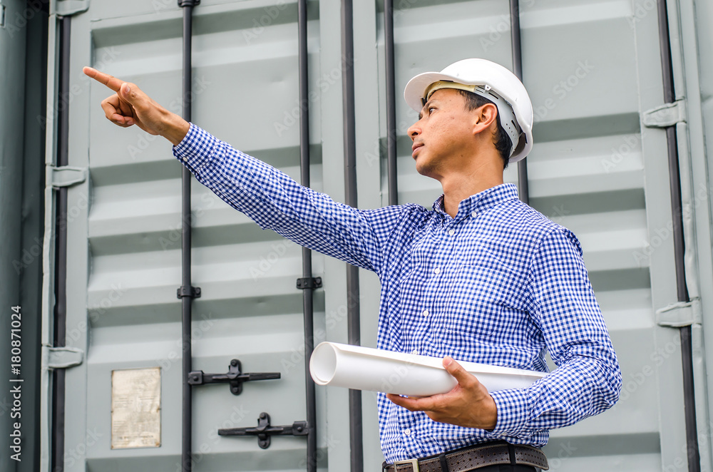 Male architect and blueprints with white helmet pointing finger on a ...