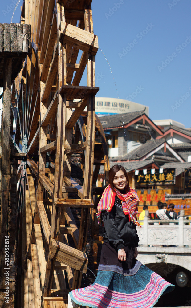chinese girl model at Lijiang dancing in front of big waterwheel woman ...