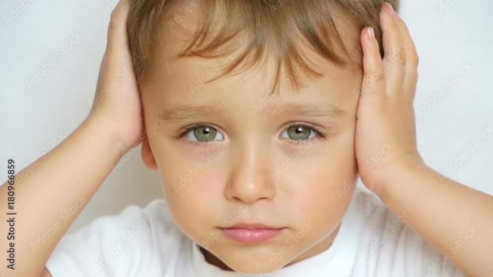 A close-up of a child looks thoughtfully at the camera, holding his ...