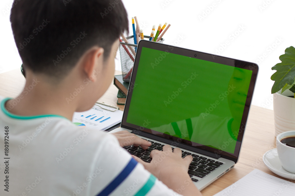 Over the shoulder shot of an Asain boy typing on a computer laptop with ...