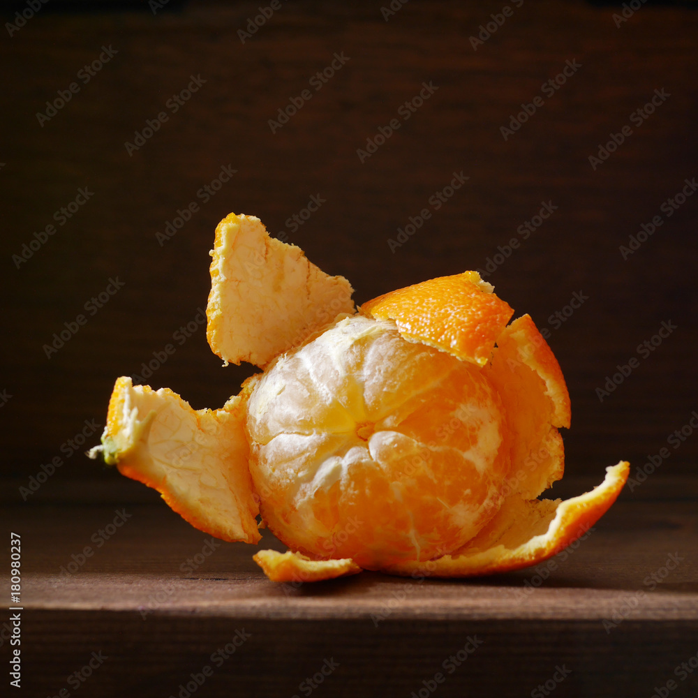 Peeled mandarin on a wooden dark background. Fruit of tangerine without ...