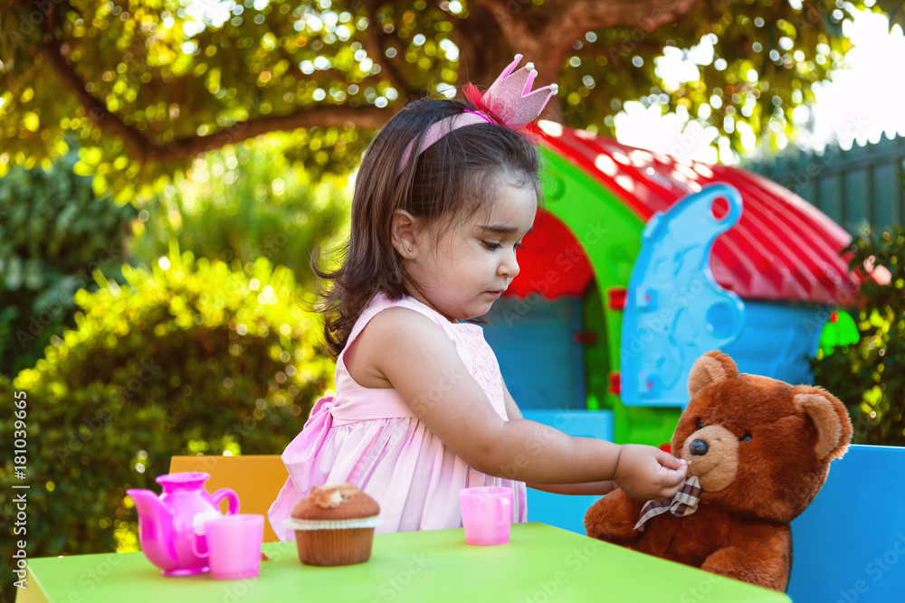 Baby toddler girl playing in outdoor tea party feeding her best friend ...