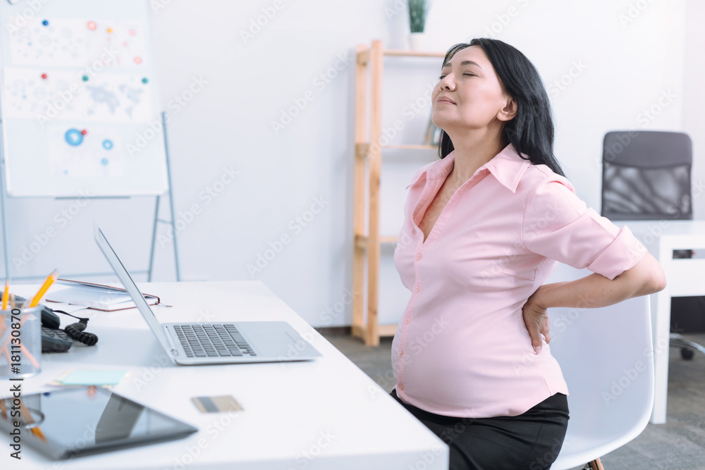 Want to relax. Pretty woman touching her back and raising head while ...