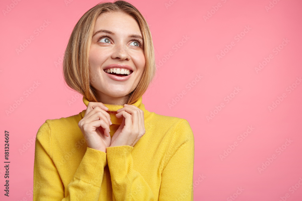 Excited young female model wears yellow polo neck sweater, has broad ...