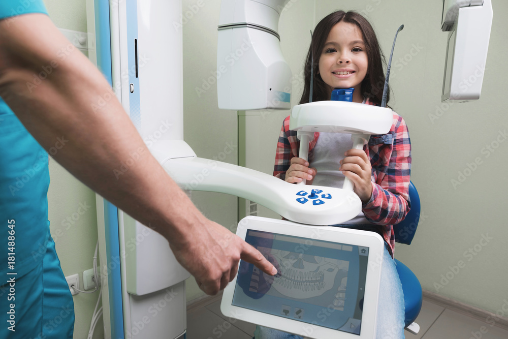 A male doctor makes an x-ray of the girl's jaw, which sits in a special ...