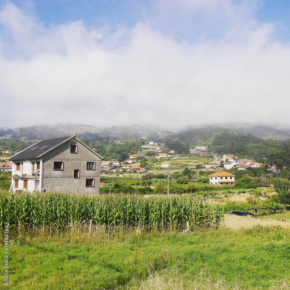 Countryside view with corn field, buildings, hills and clouds foto de ...