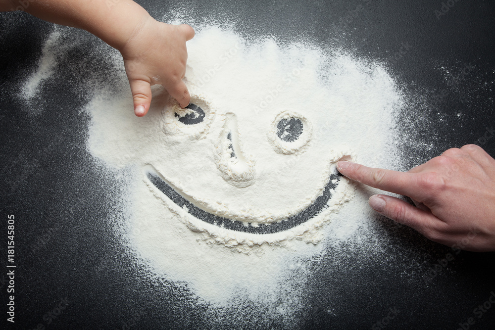 Mom and daughter painted a smiley face on flour. Stock Photo | Adobe Stock