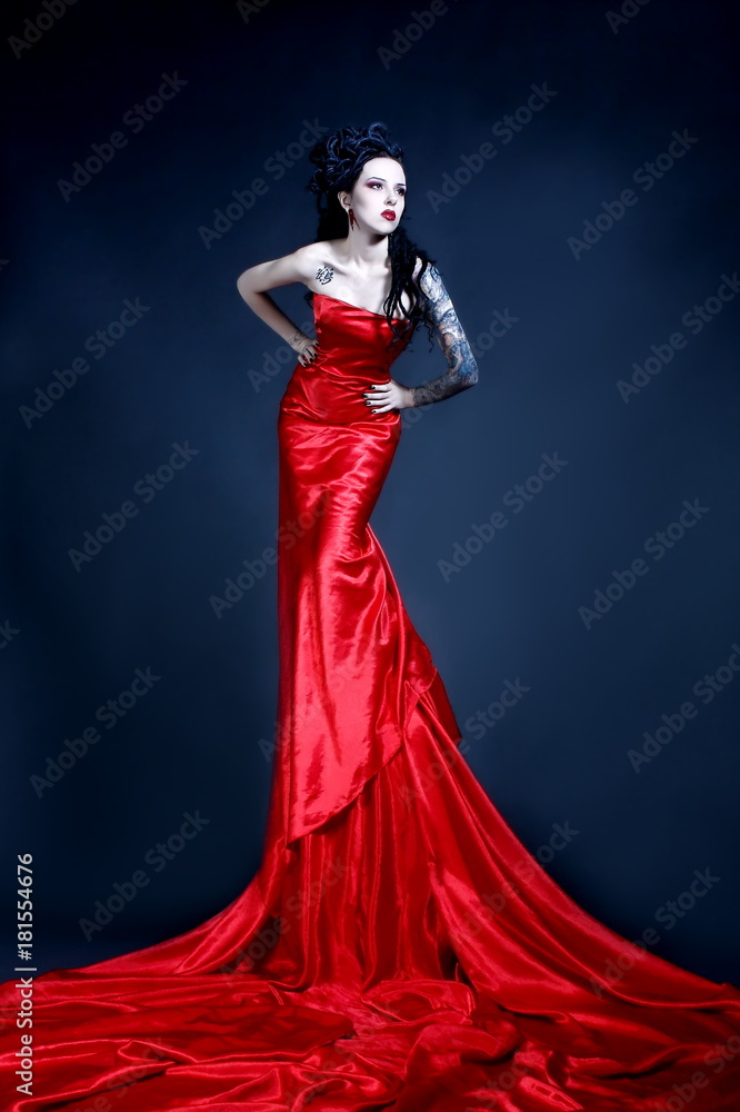 Beautiful young girl with a tattoo on her shoulder in a red dress ...