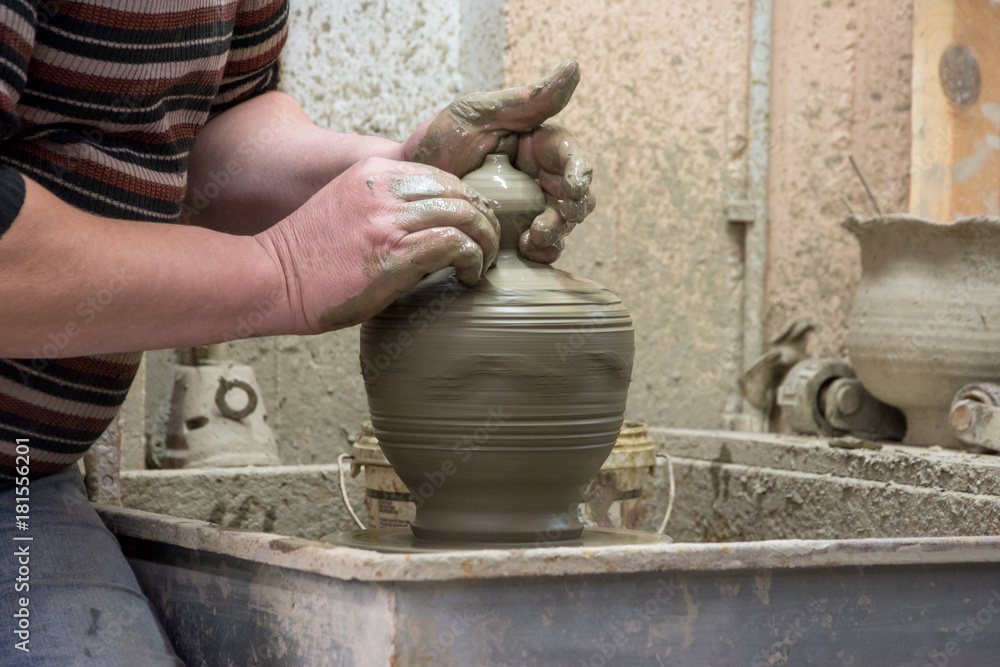 Man potter at work creating some traditional cups of white clay ...