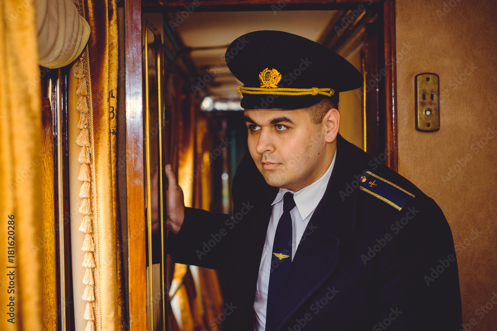 European or American train conductor is on his duty on a platform and ...
