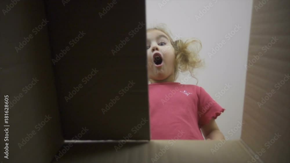 A little girl looks in the box, is surprised and happy to receive a ...