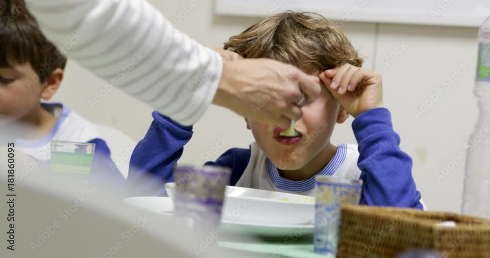 Casual candid moment of handsome child being given healthy vegetable ...