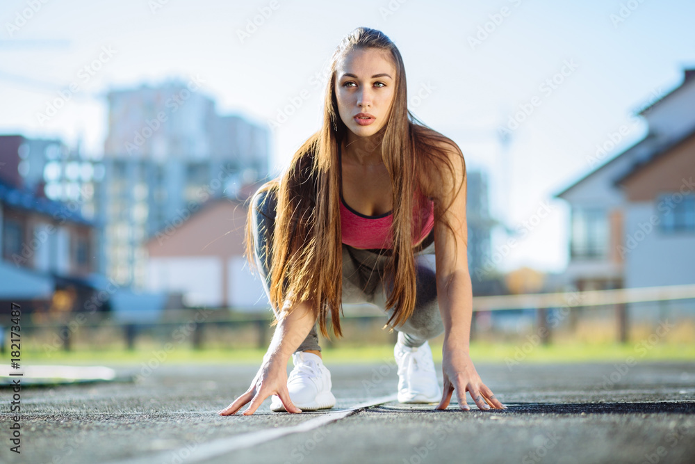 Confident gorgeous teenager girl in starting position ready for running ...