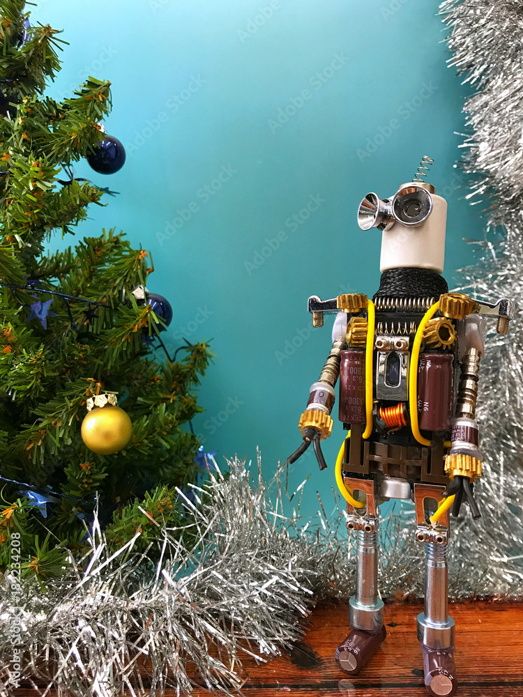 Robot standing beside Christmas tree with hands full of decorations ...