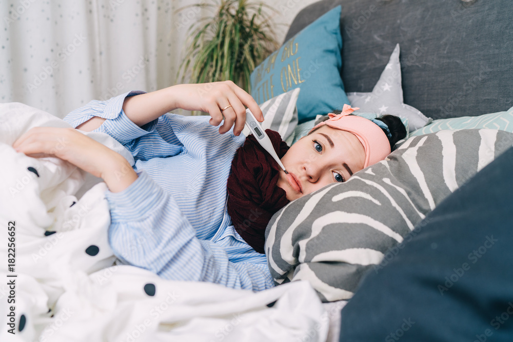 Sick woman in bed with thermometer is having high temperature/fever ...
