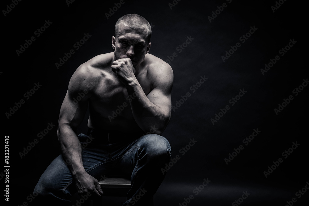 portrait of a seated male bodybuilder, on a black background isolated ...