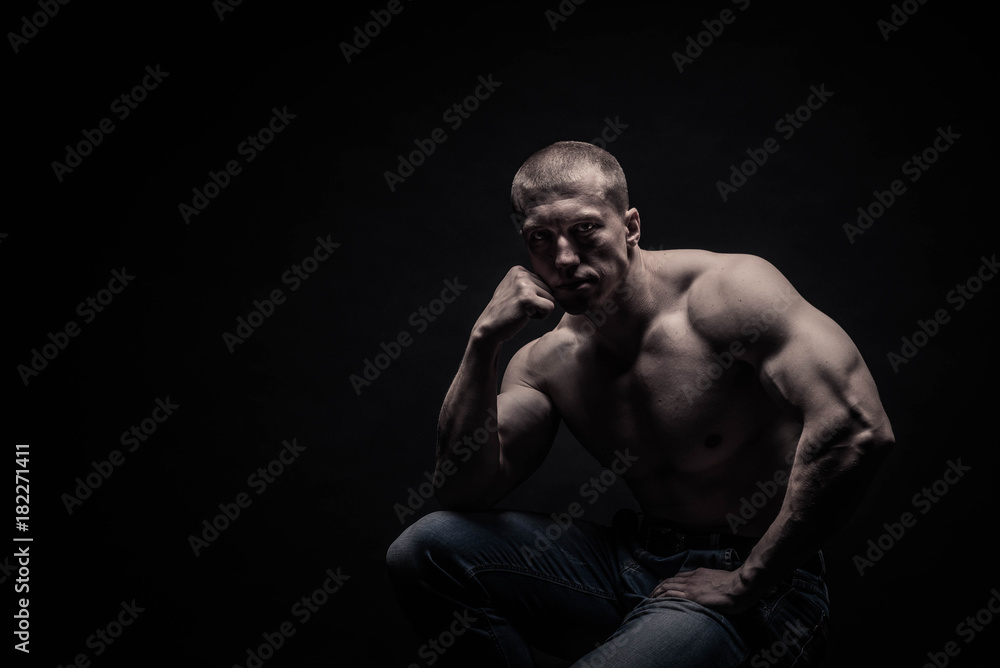 portrait of a seated male bodybuilder, on a black background isolated ...