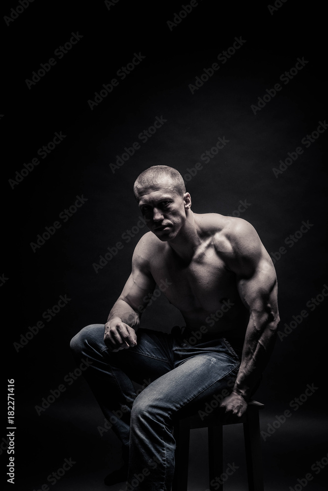 portrait of a seated male bodybuilder, on a black background isolated ...
